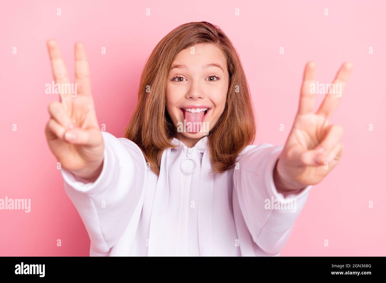 Portrait of attractive cheerful girl showing double v-sign grimacing ...