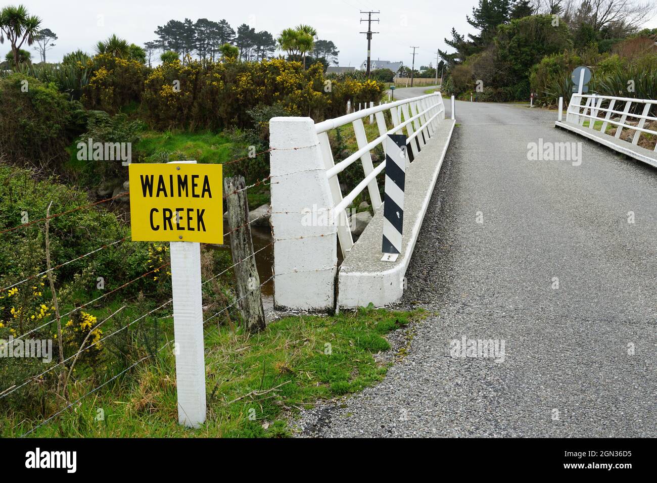 Yellow sign saying 'Waimea creek' before the bridge Stock Photo - Alamy