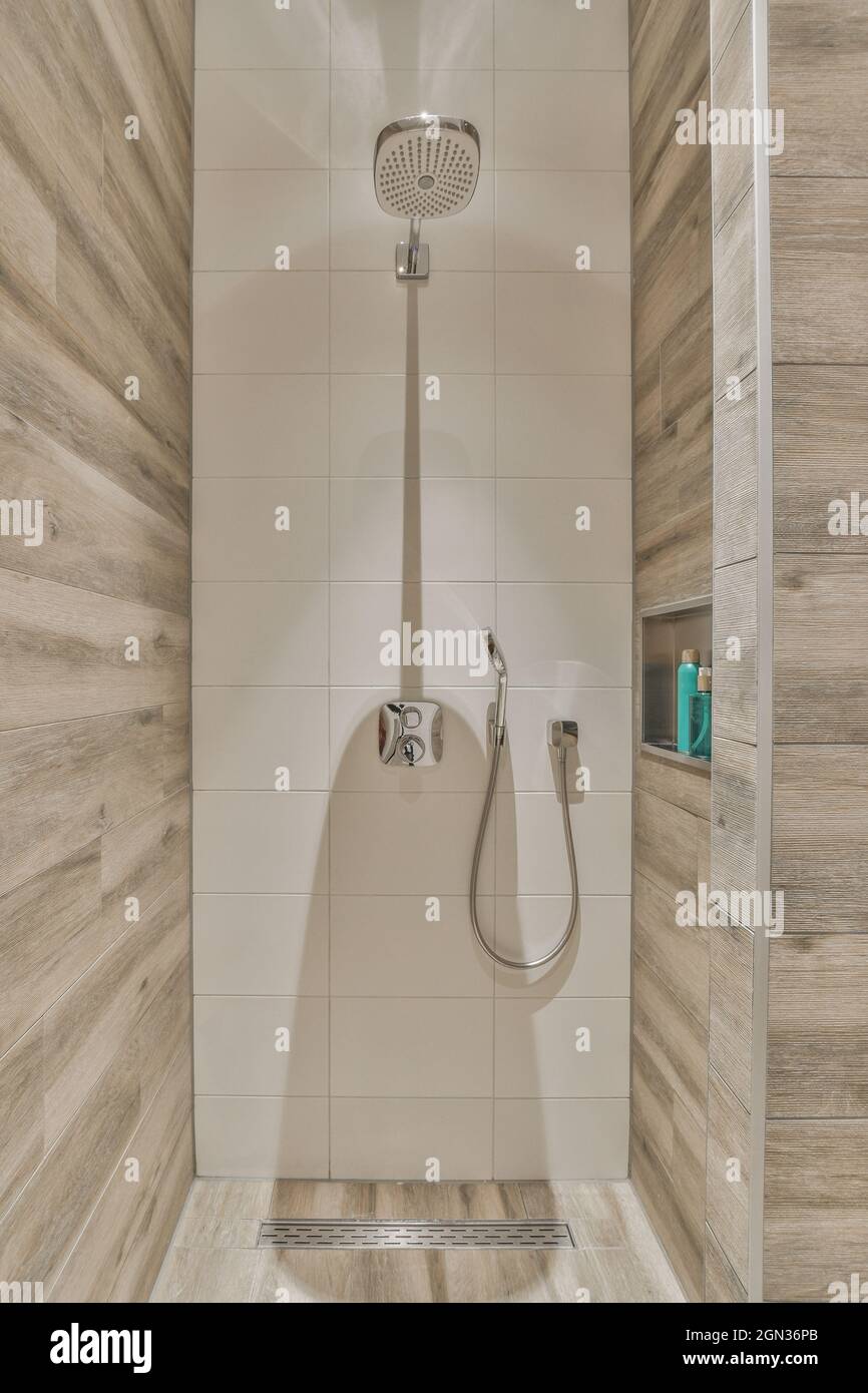Shower unit and toiletries in bathroom with tiled walls in modern ...