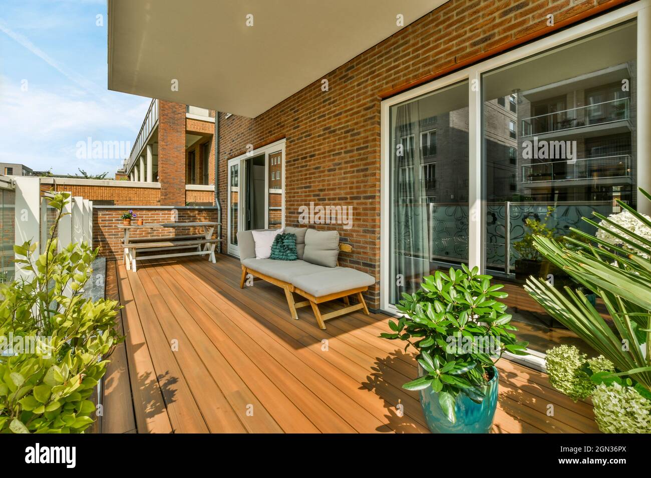 Couch and table on veranda of residential cottage with potted plants ...