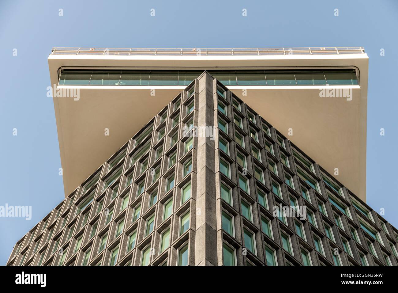 From below of high multistory building with unusual windows under blue ...