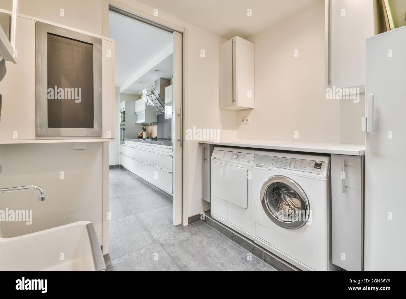 Washing machine and dryer against tiled floor and washbasin in ...