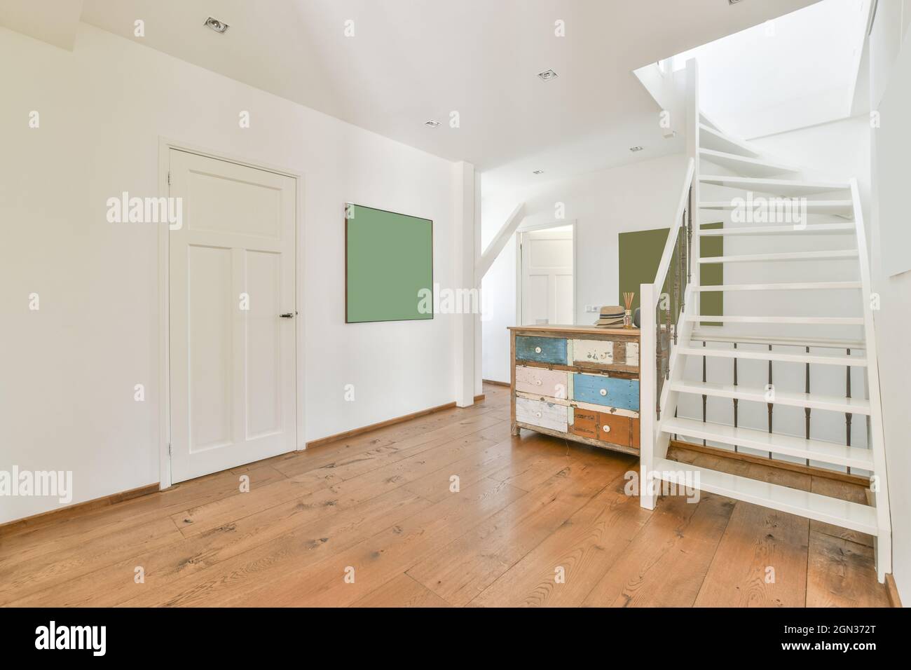Wavy white staircase above parquet with aged table against panel and ...