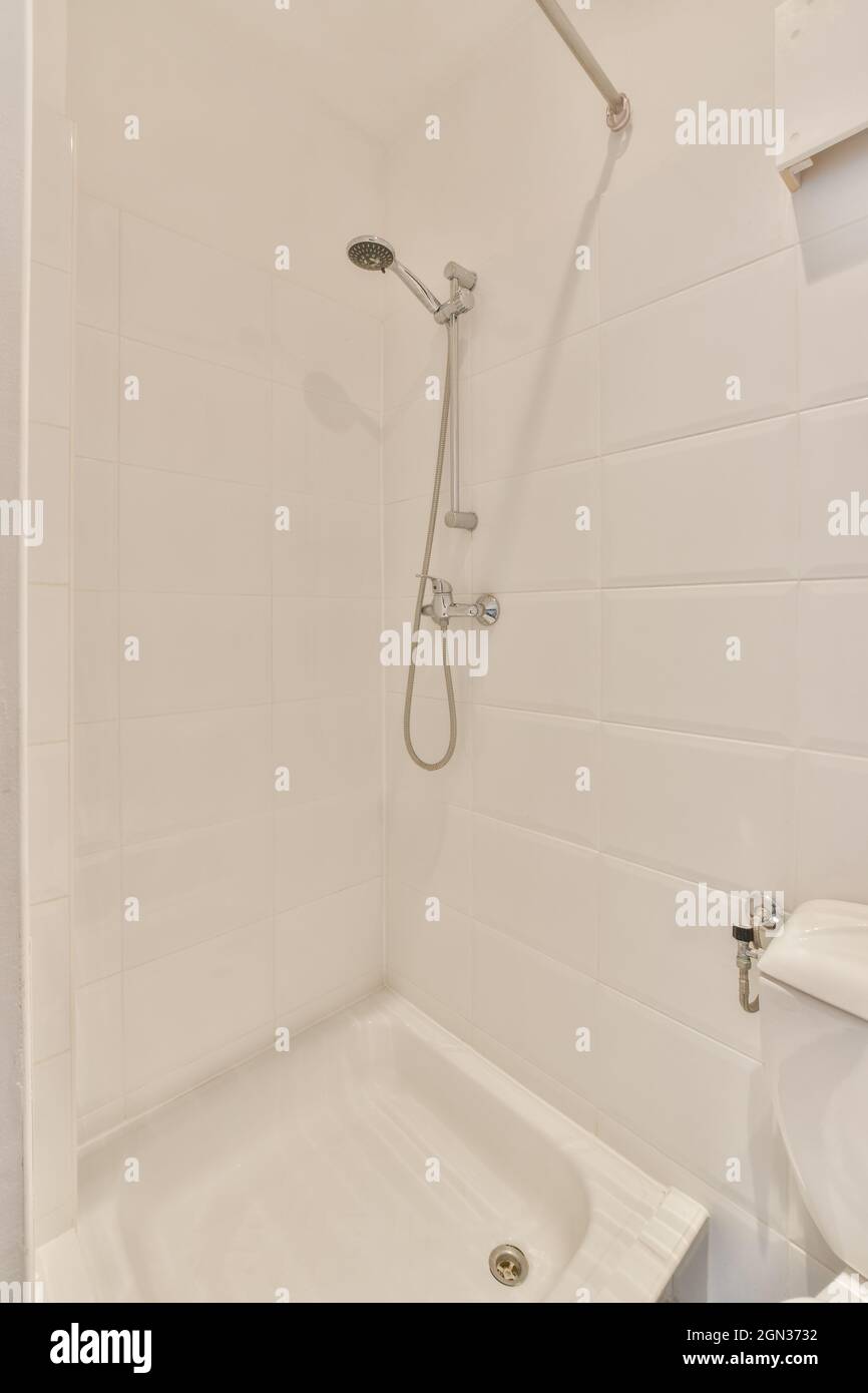 Interior of empty bathroom with shower unit and light tiled walls in ...