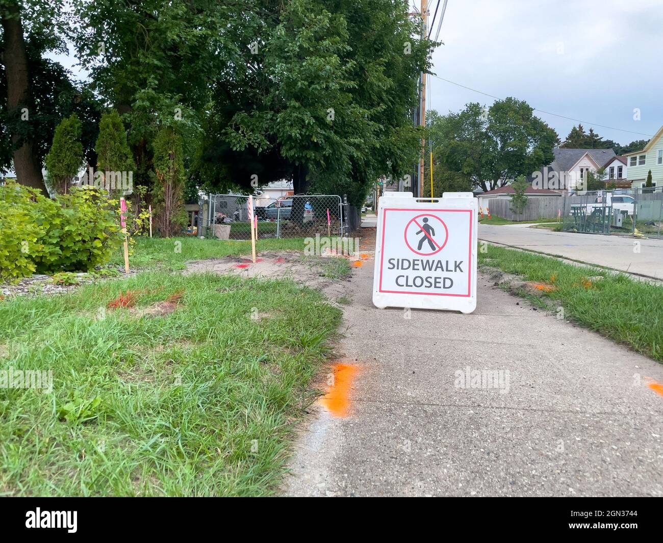 Sidewalk closed sign by the road and lawn on the background of houses ...