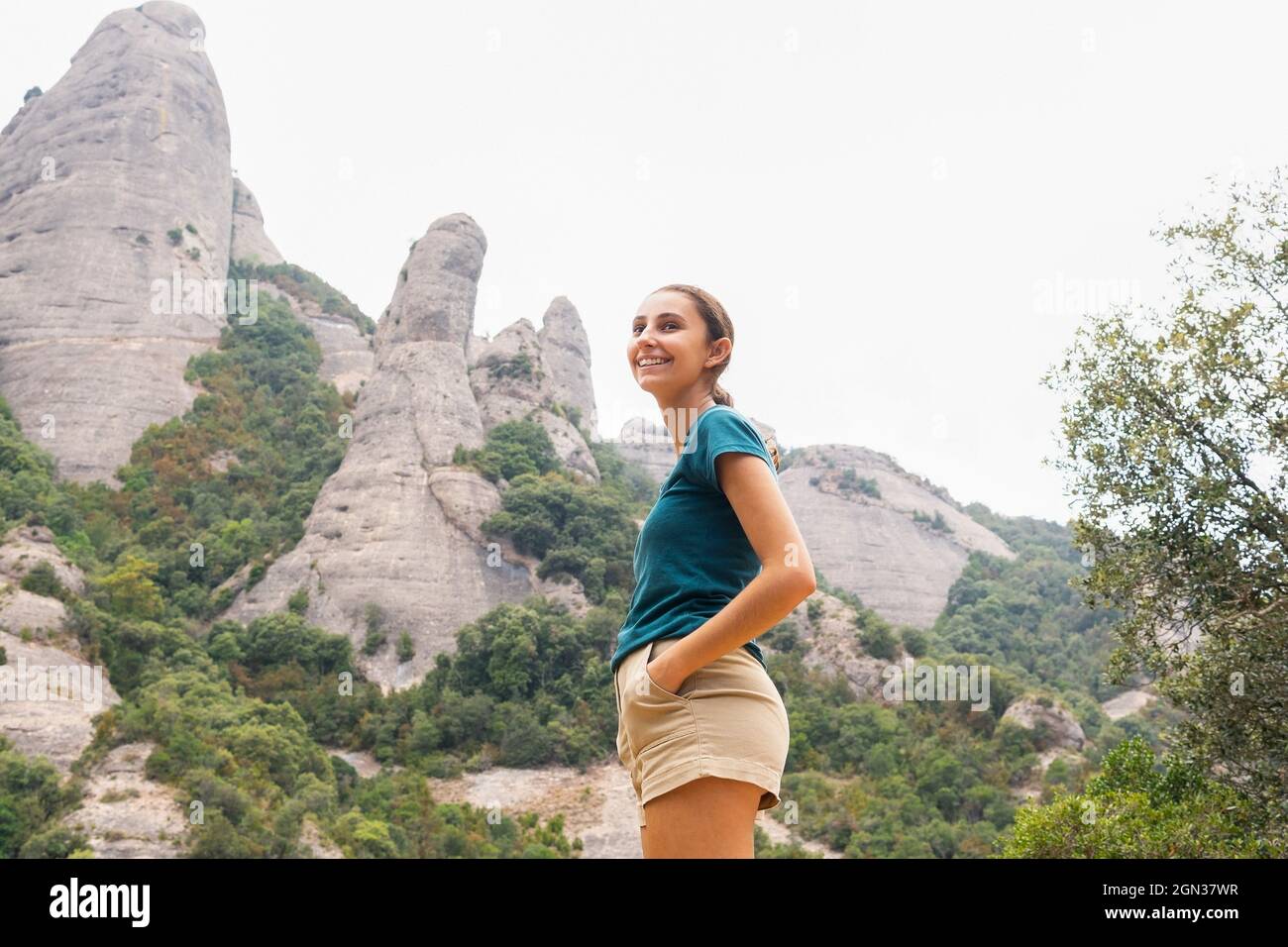 Side view of cheerful female traveler with hands on hips contemplating ...