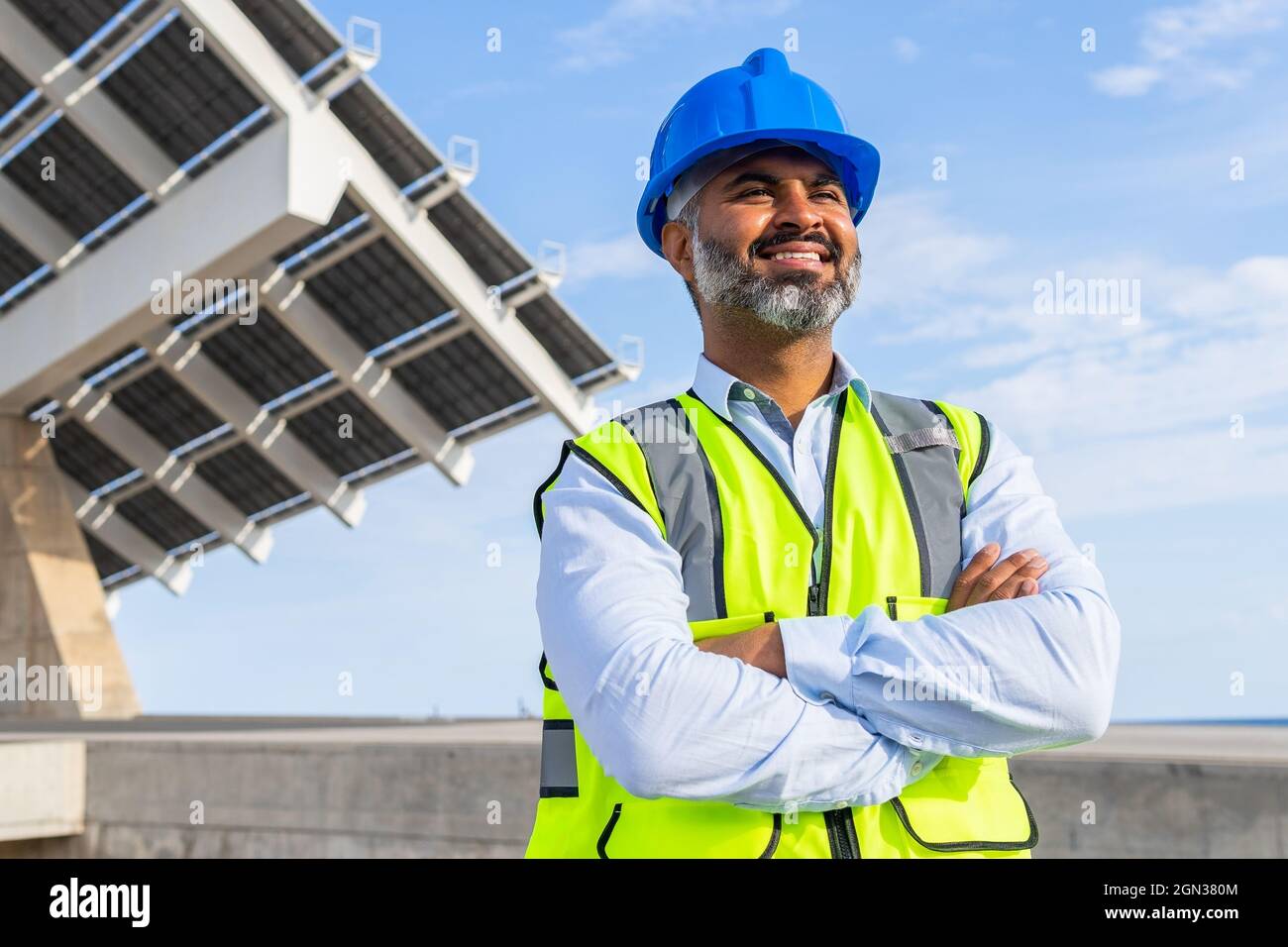 Low angle of delighted ethnic male inspector in vest with protective ...