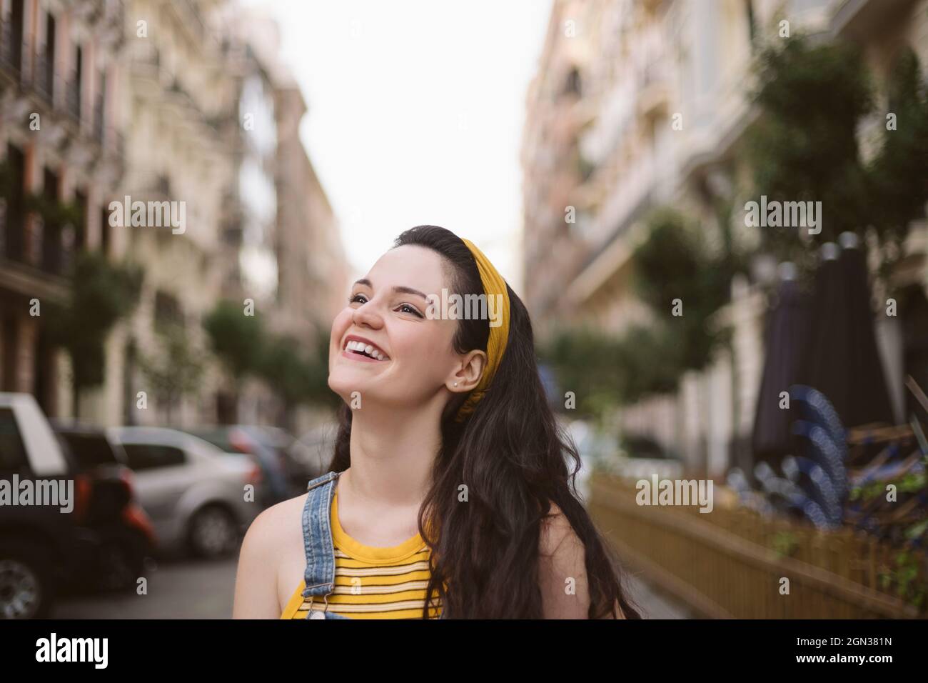 Young happy female with long brown hair wearing denim overall walking ...
