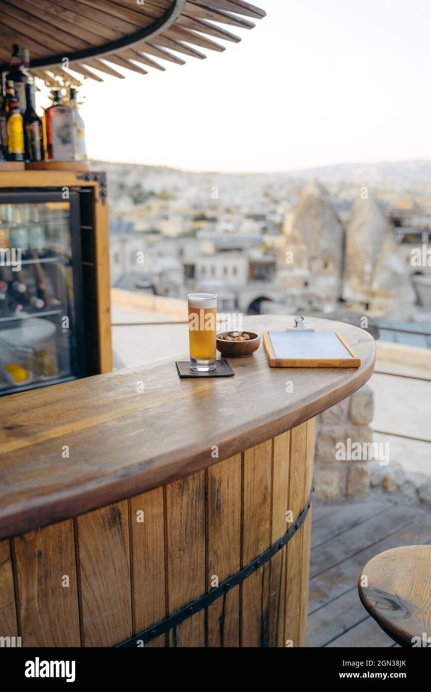Glass of cold beer with snacks and menu placed on wooden round counter ...