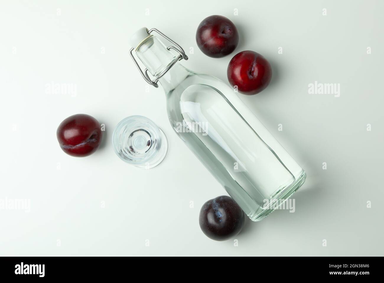 Bottle and shot of plum vodka and ingredients on white background Stock ...