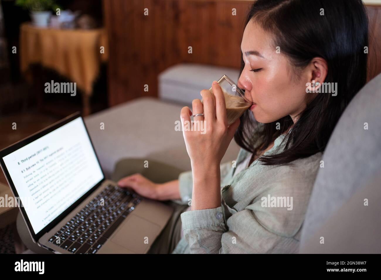 Side view of interested young ethnic female remote employee working on ...