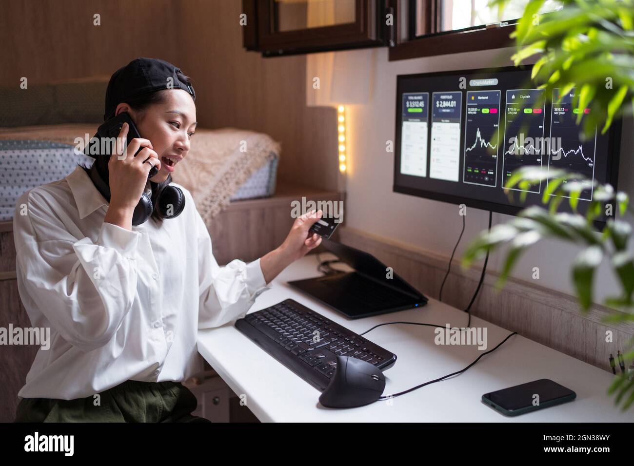 Surprised Asian female trader speaking on smartphone and looking at ...