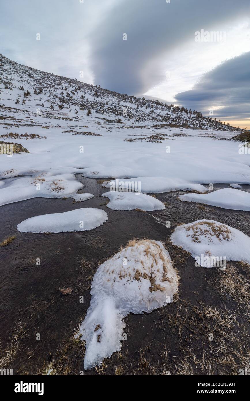 Landscape of snowy slope of hill in highland under cloudy sky in ...