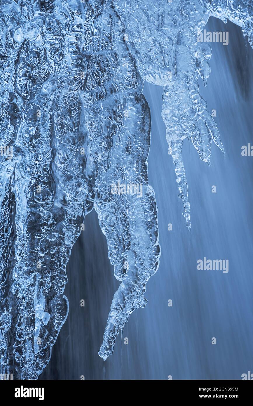 Texture of cold uneven clear ice above water stream flowing in winter ...