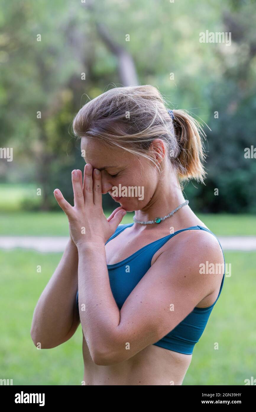 Side view of young female in activewear standing with namaste hands ...