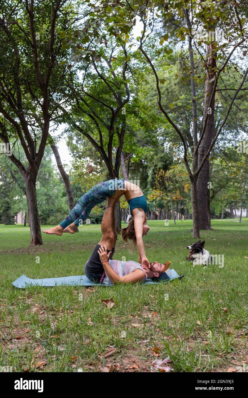 Side view of concentrated couple in sportswear practicing acroyoga on ...