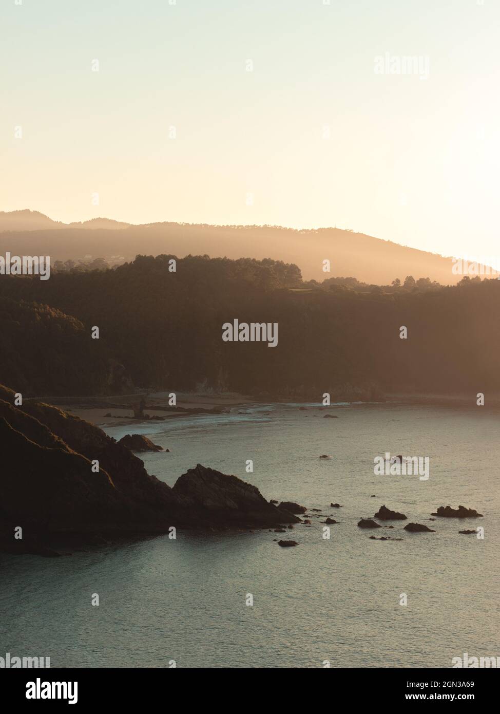 Scenery view of mount silhouettes against wavy ocean under sunset sky ...