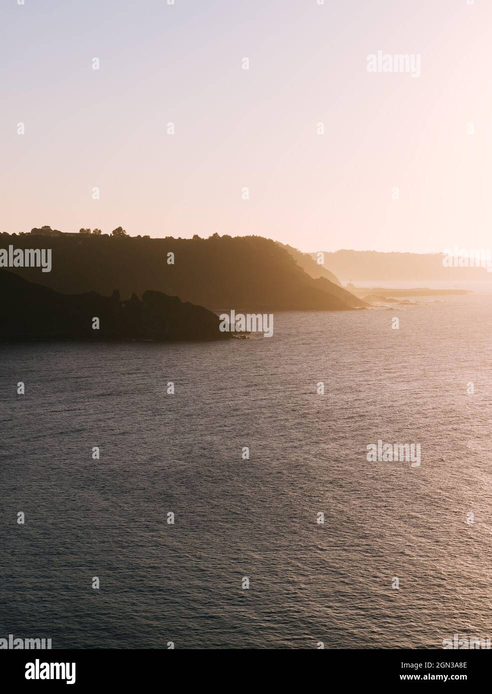 Scenery view of mount silhouettes against wavy ocean under sunset sky ...