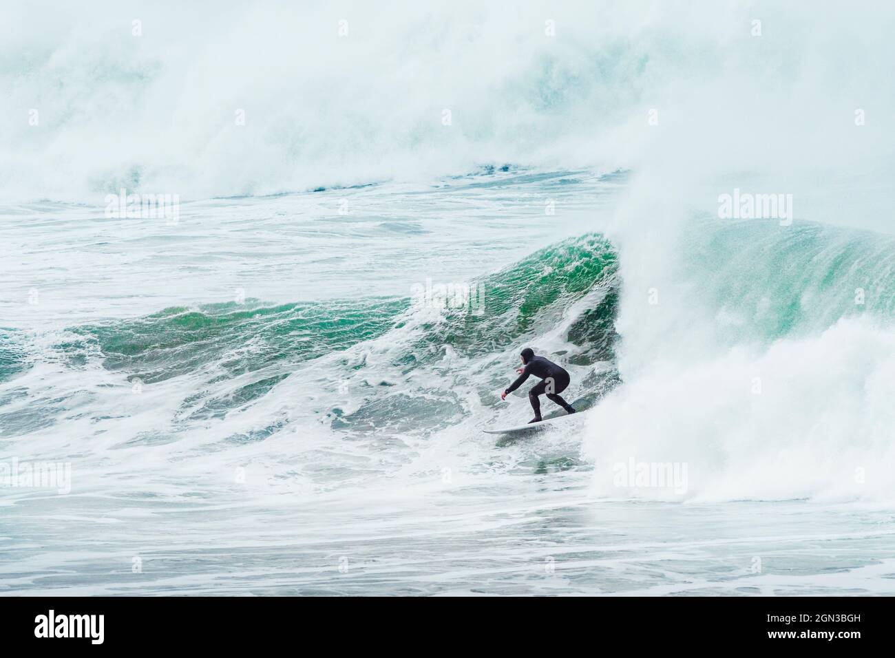 A surfer riding huge waves building over the Cribbar Reef off the coast ...