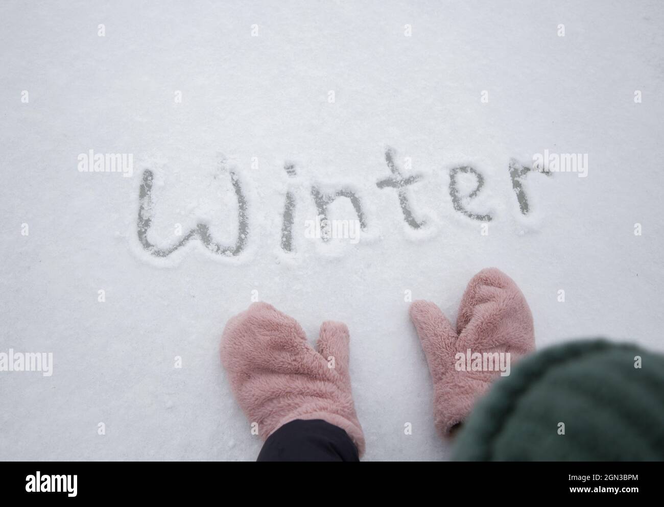 word winter written on the snow and women's hands in pink fluffy ...