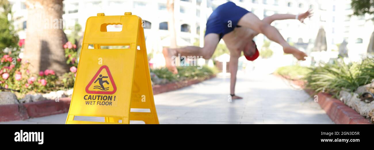 Yellow sign caution wet floor standing near falling man closeup Stock ...