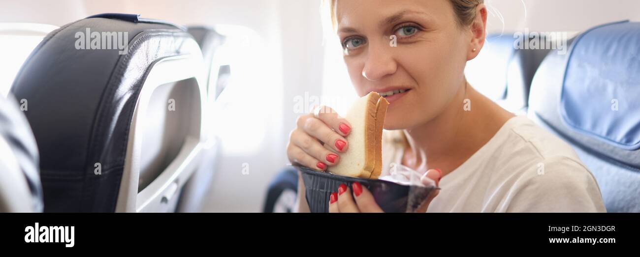 Young woman flying in airplane and eating sandwich Stock Photo - Alamy