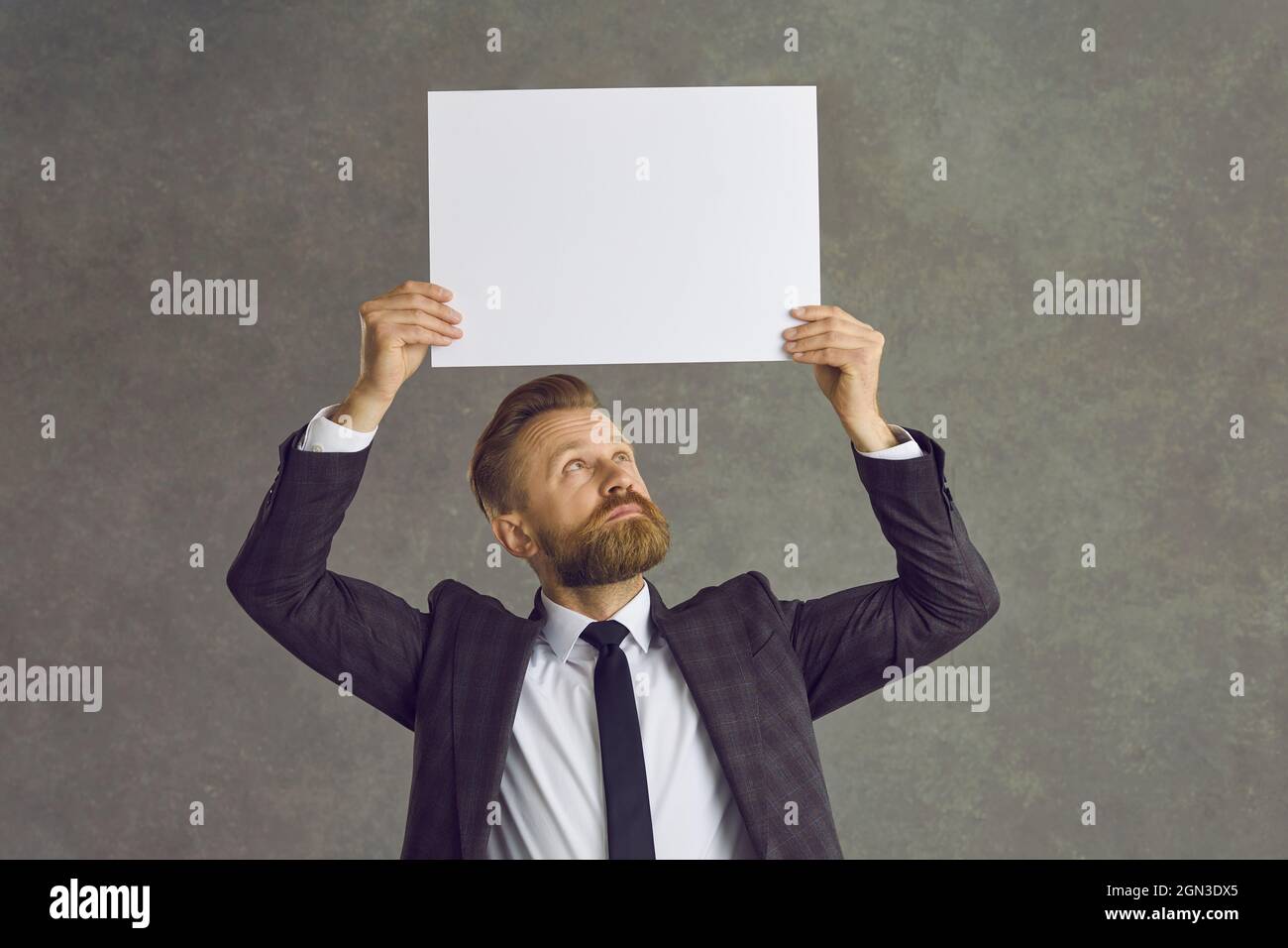 Caucasian businessman holding a blank white sheet of paper over his ...