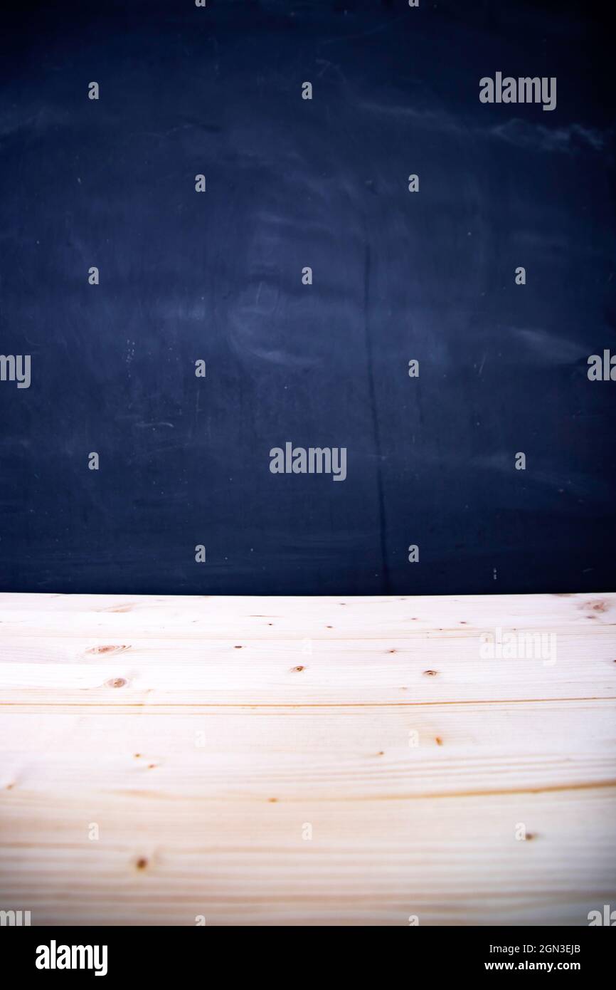 Wooden table with blackboard background Stock Photo - Alamy