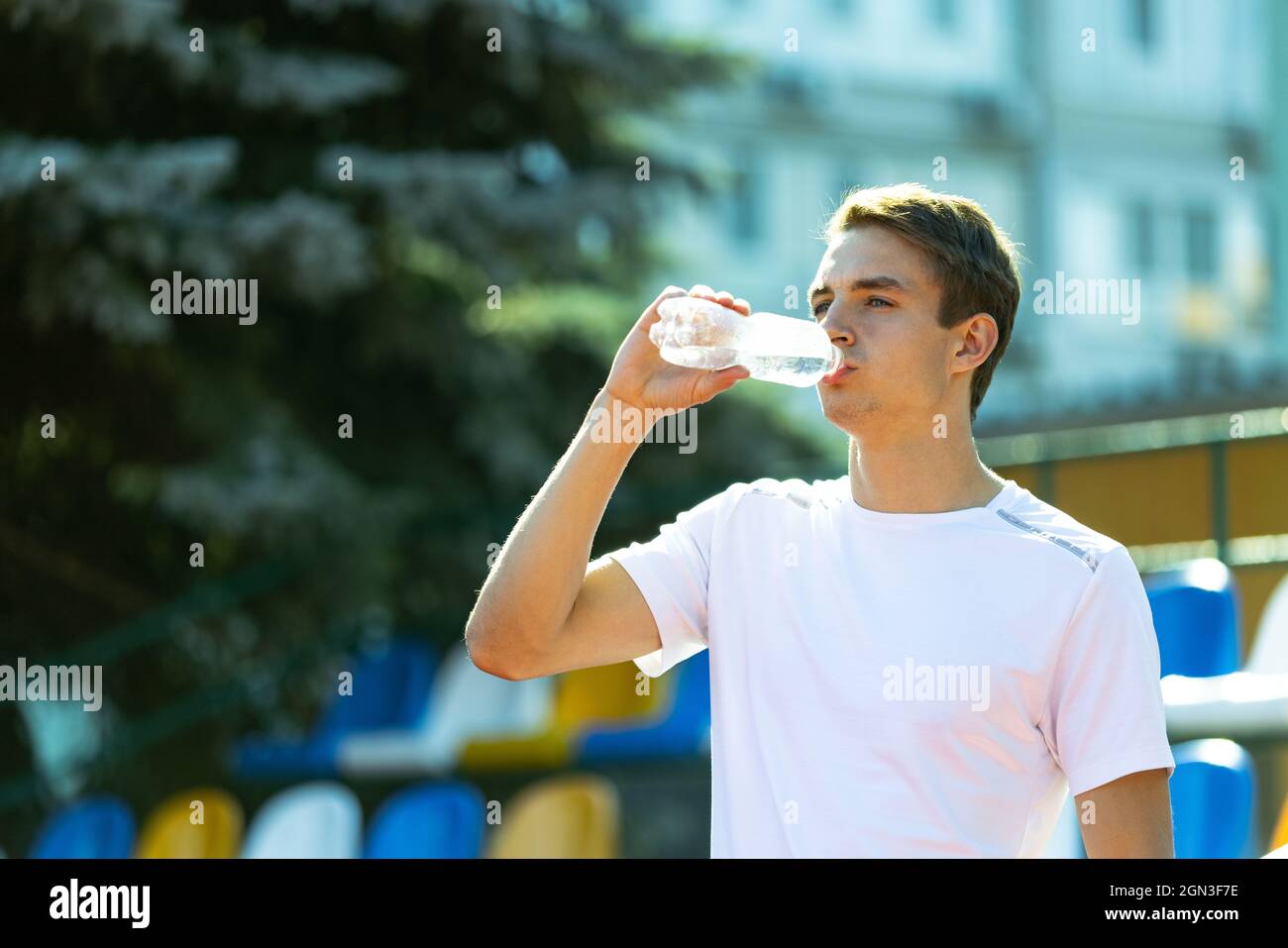 Close-up young Caucasian man, male athlete, runner at public stadium ...