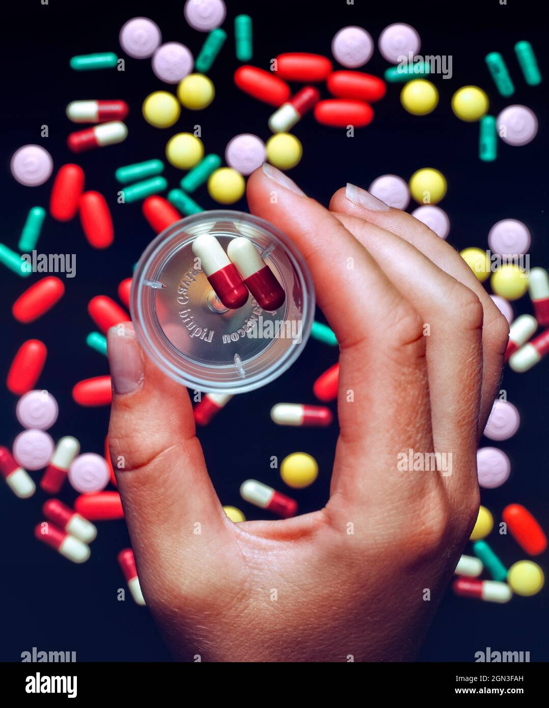 A woman's hand holding a dispensing container of red & white ...