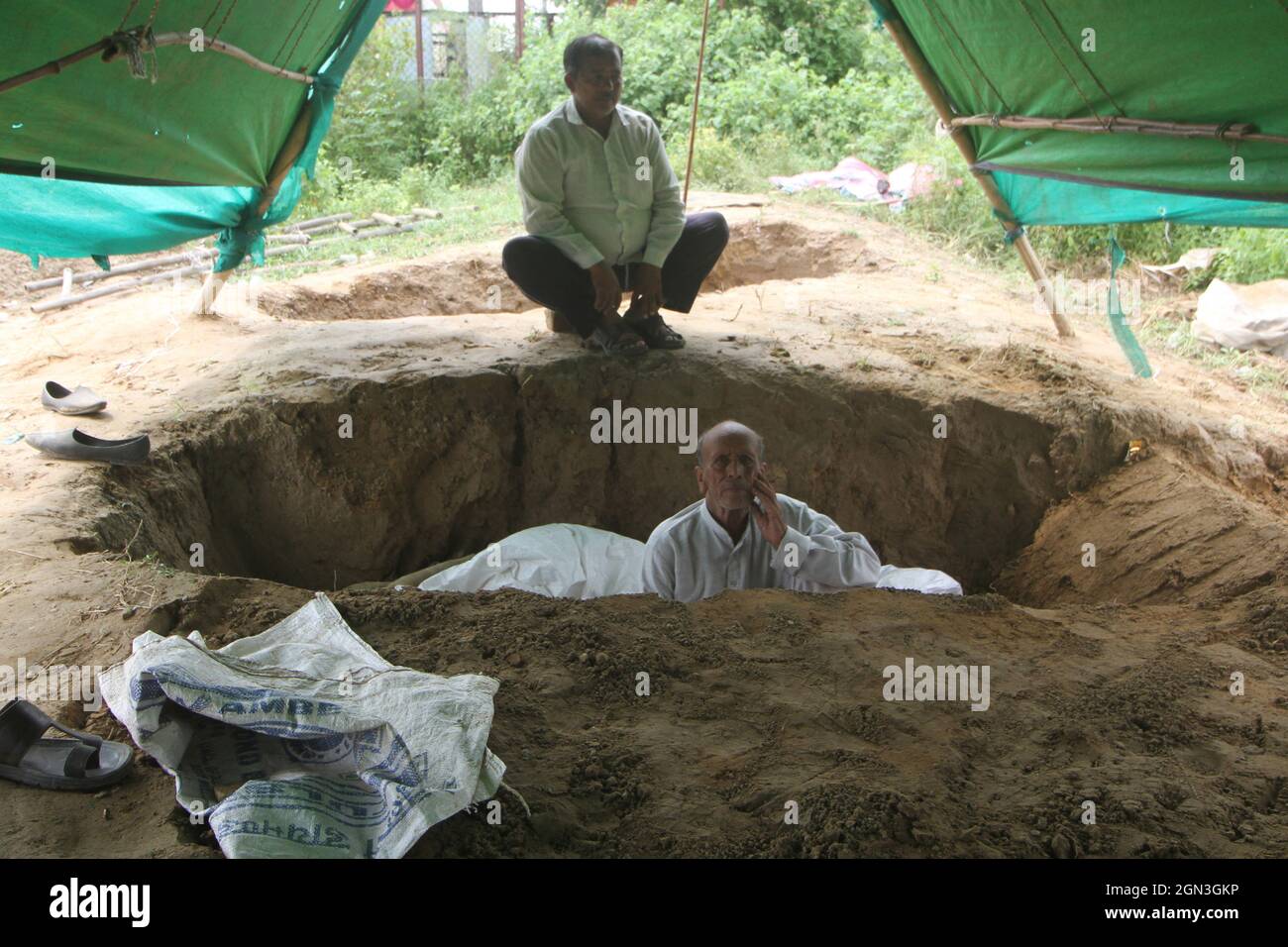 A farmer sits in a grave dugged as part of protests against the farm ...