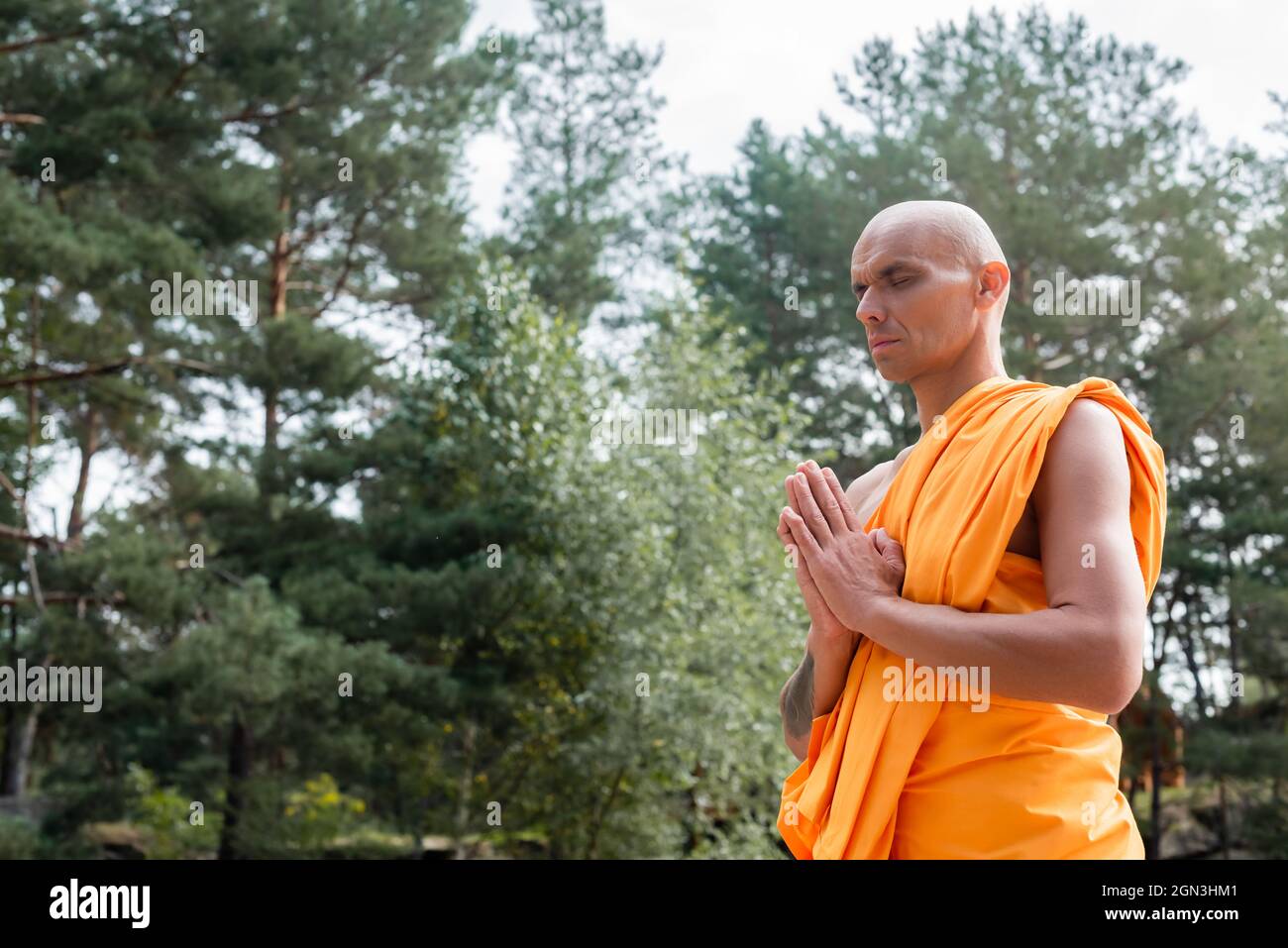 buddhist in orange robe praying with closed eyes outdoors Stock Photo ...