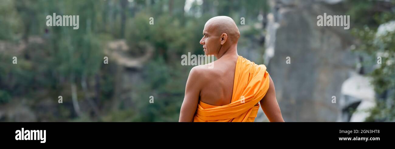 back view of buddhist monk looking away while meditating outdoors ...