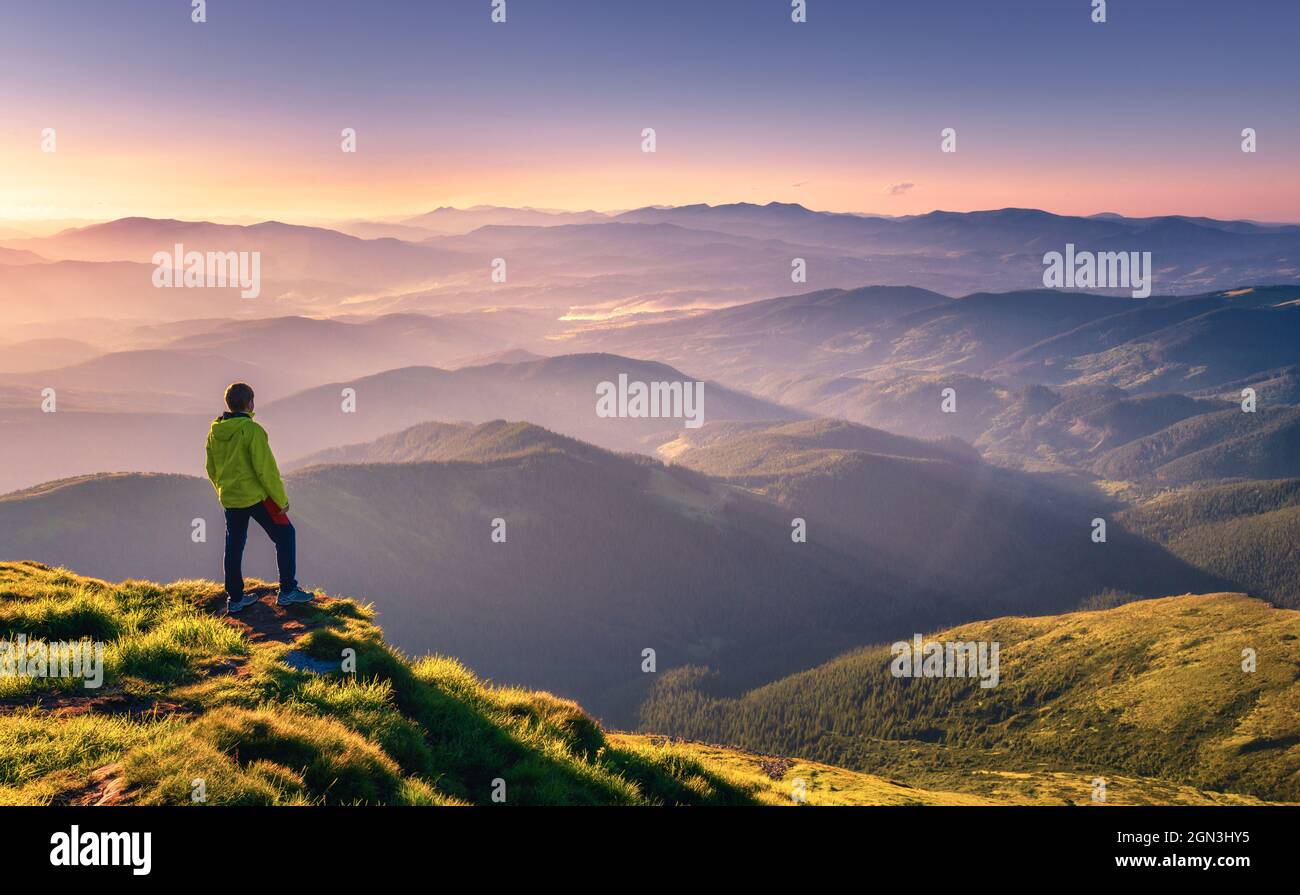 Sporty man on the mountain peak looking on mountain valley Stock Photo ...