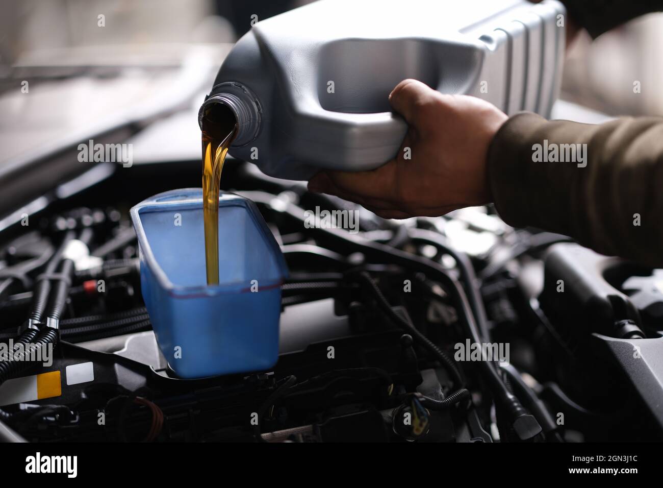 Master repairman pouring motor oil into car engine closeup Stock Photo ...