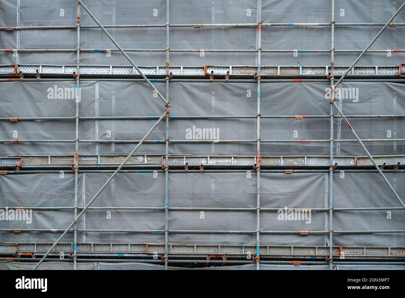 Building covered with scaffolds and grey mesh Stock Photo - Alamy
