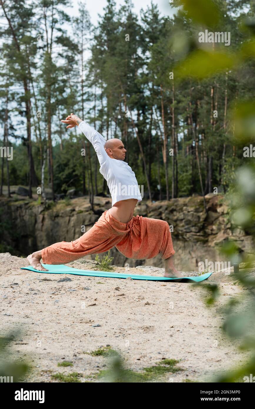 full length view of buddhist practicing warrior pose with raised hands ...
