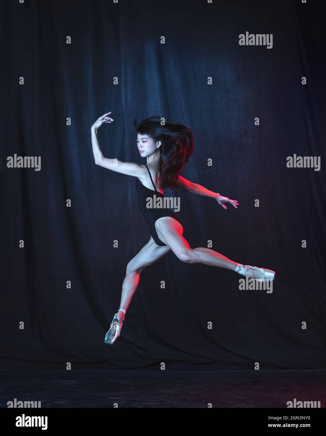 Young and graceful female ballet dancer in motion isolated on dark ...
