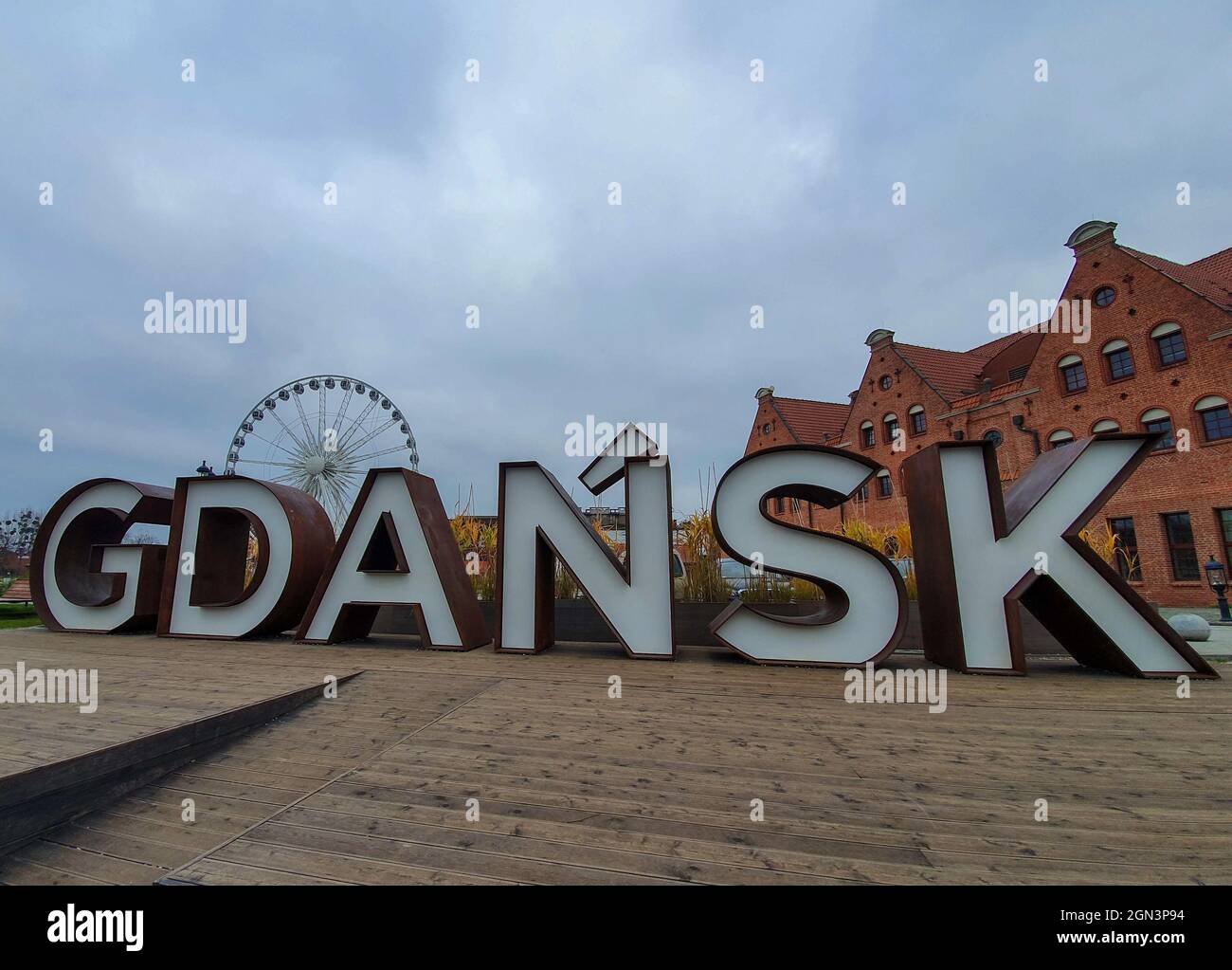 A giant Gdansk sign in front of a ferris wheel and traditional brick ...