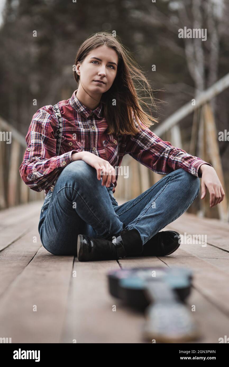 Young woman sitting whith ukulele guitar on bridge in autumn forest ...