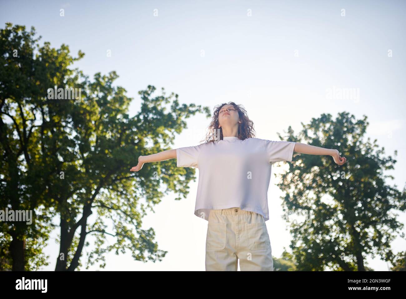 A girl in white standing with arms open wide Stock Photo - Alamy