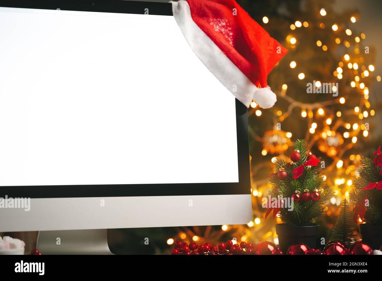Wooden desk with computer with blank screen against blurred christmas ...