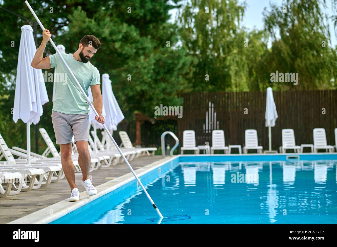 A service person cleaning the swimming pool and looking busy Stock ...