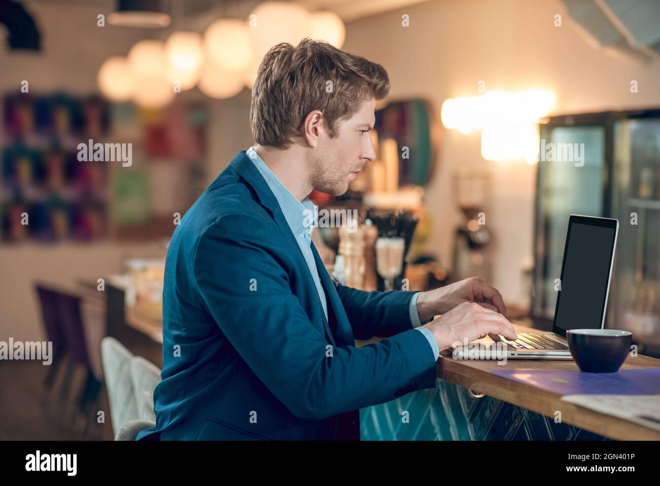 Profile of man looking into laptop in cafe Stock Photo - Alamy