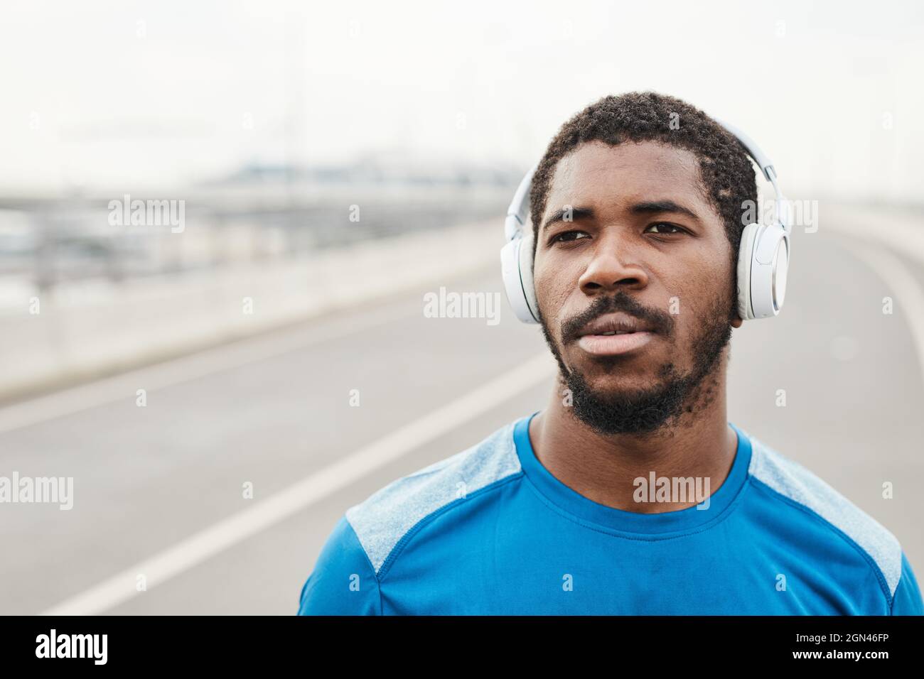 African young man putting on wireless headphones and listening to music ...