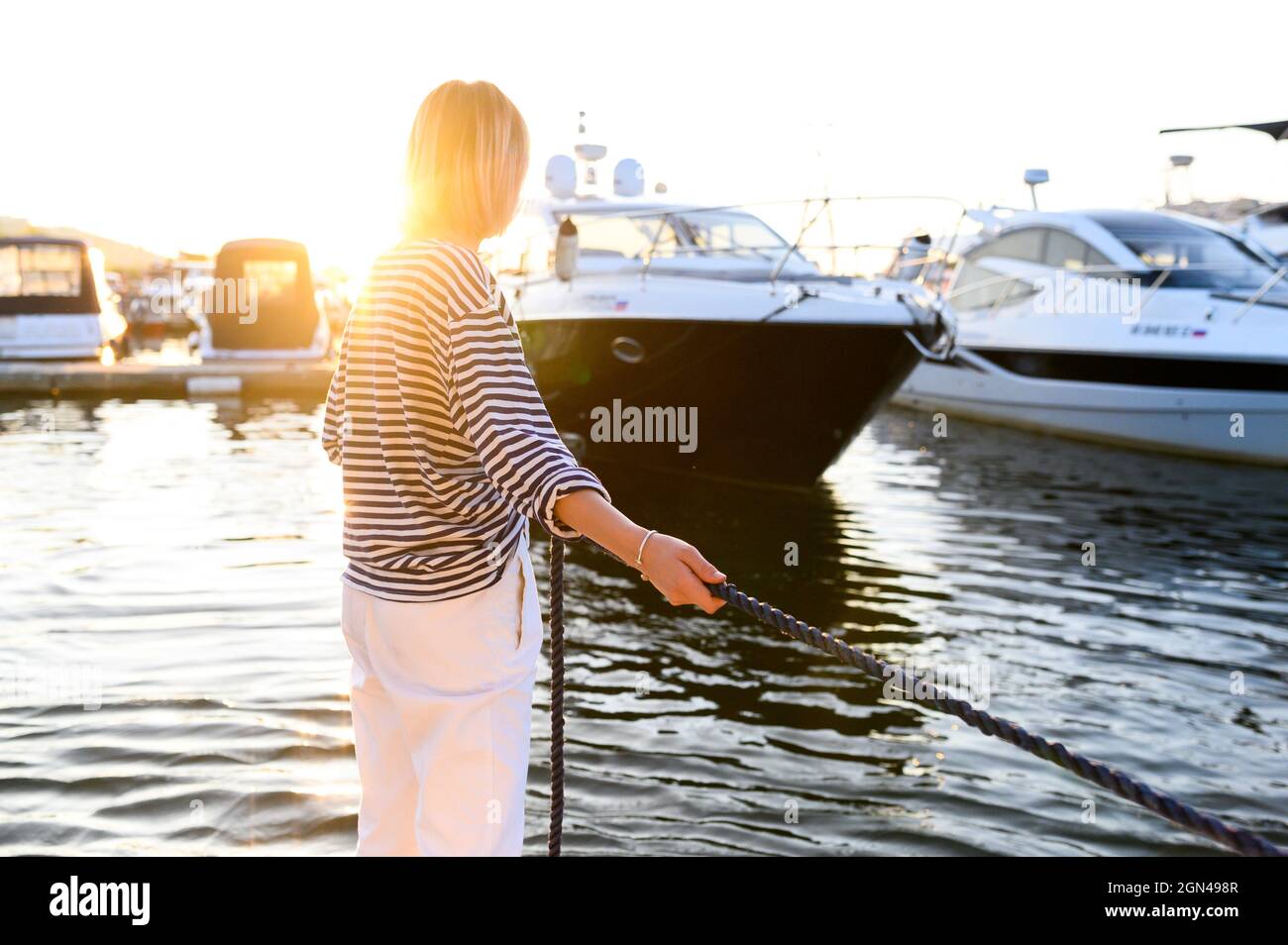 girl sailor pulls the marine rope to the yacht moored. Sea style ...