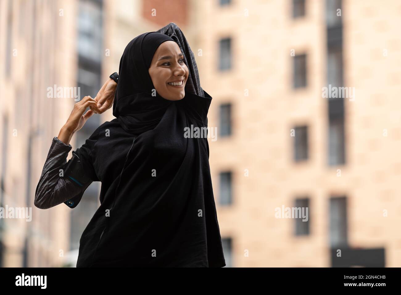 Sporty muslim woman in hijab stretching muscles, preparing for fitness ...