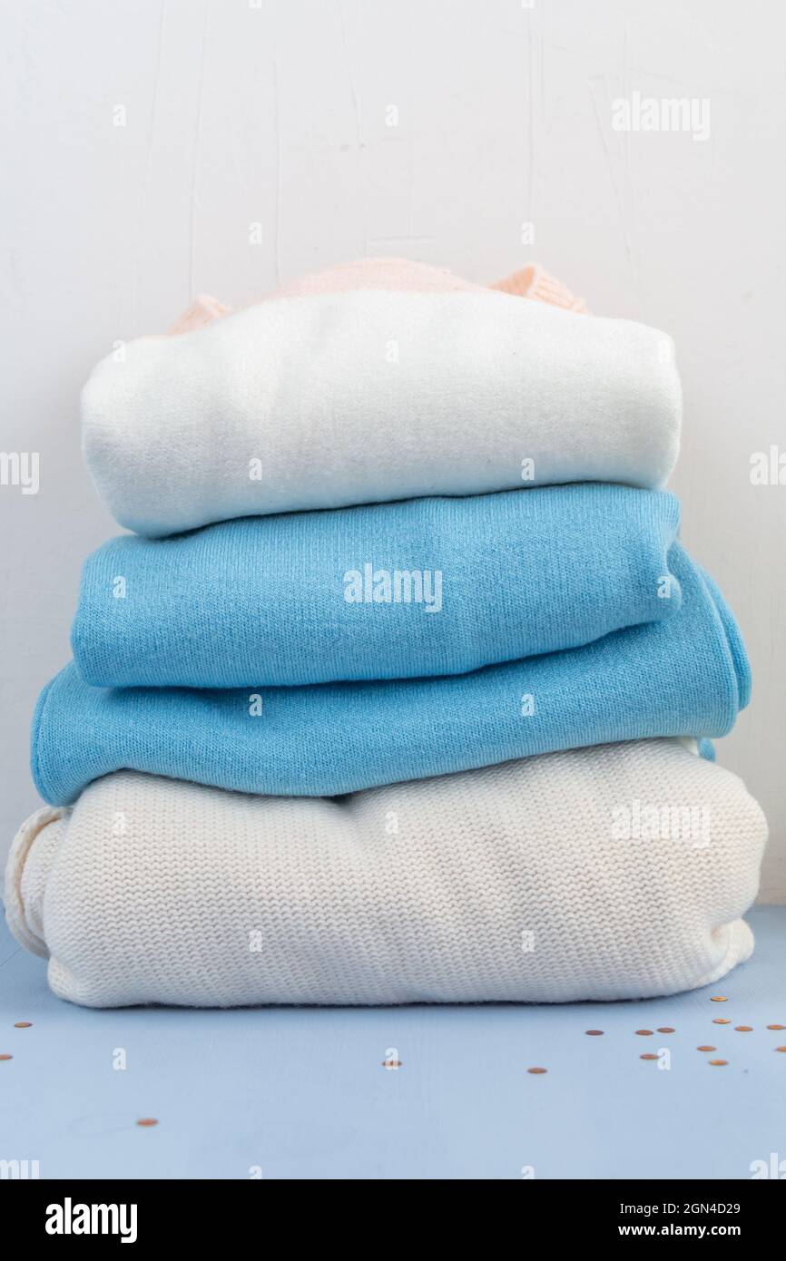 stack of cotton wool sweaters isolated on white and light blue ...