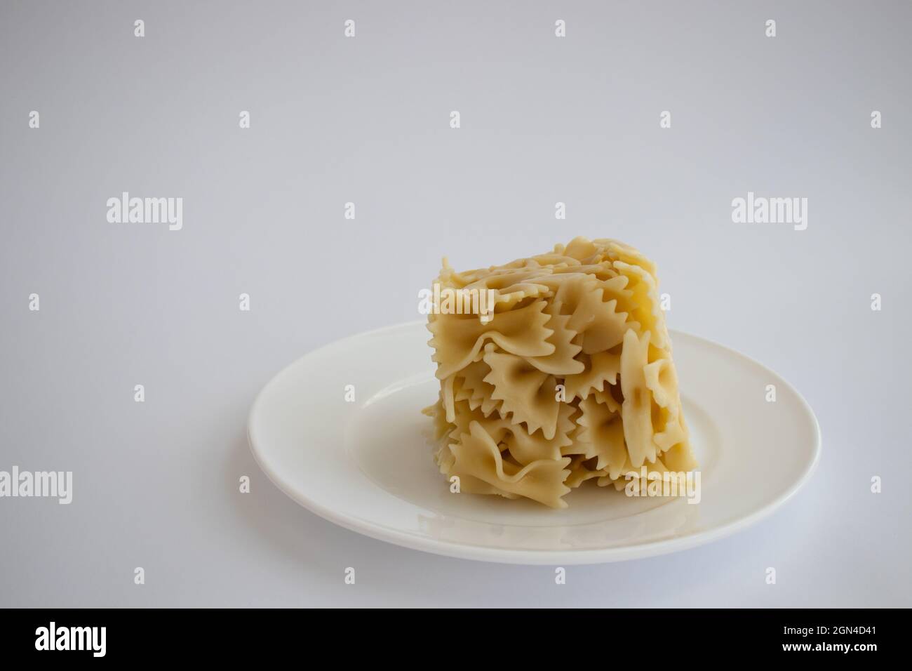 Cooked farfallini pasta in a shape of cube on a white plate. Copy space ...