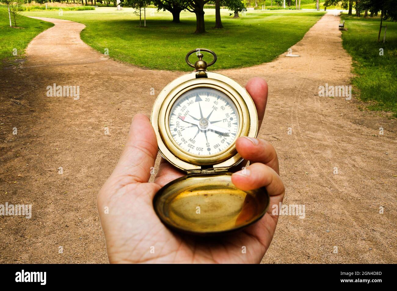 hand holding a compass in front of a crossroad, choosing a direction ...